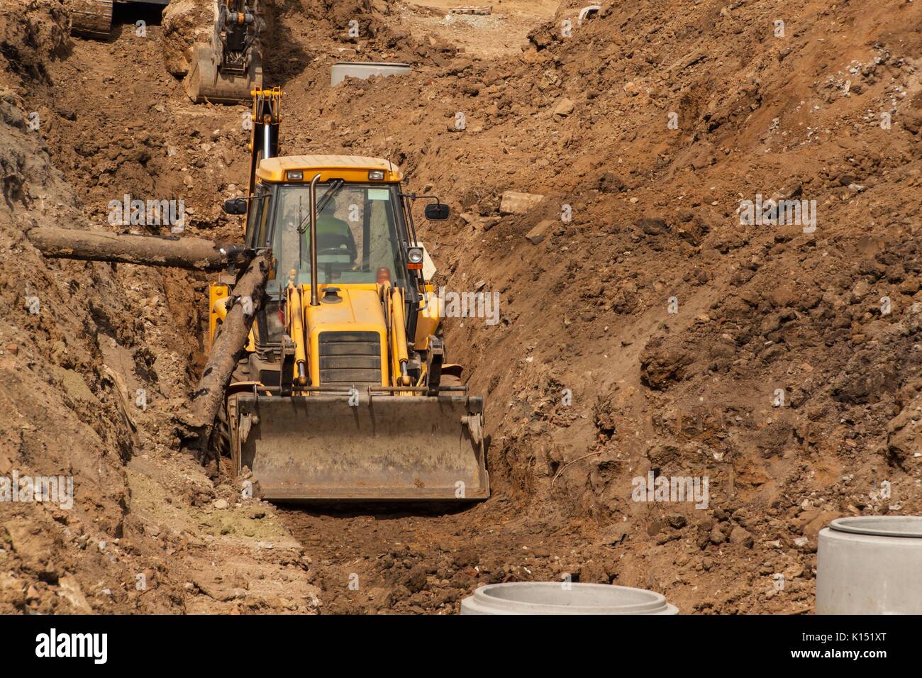 Construction of a new sewerage system. The bulldozer digs a trench for ...
