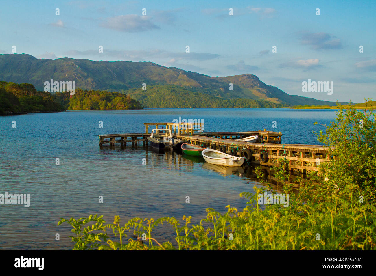 calm blue waters of Loch Morar hemmed with rugged mountains and with ...