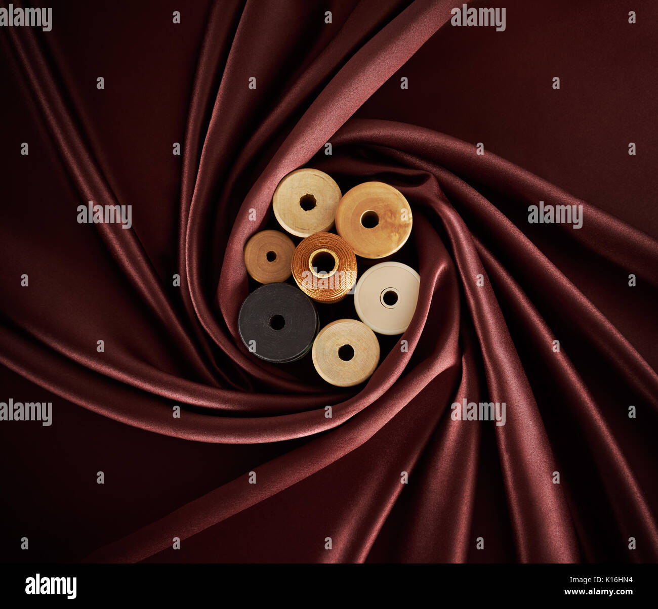 Spool of threads with silk fabric background Stock Photo - Alamy
