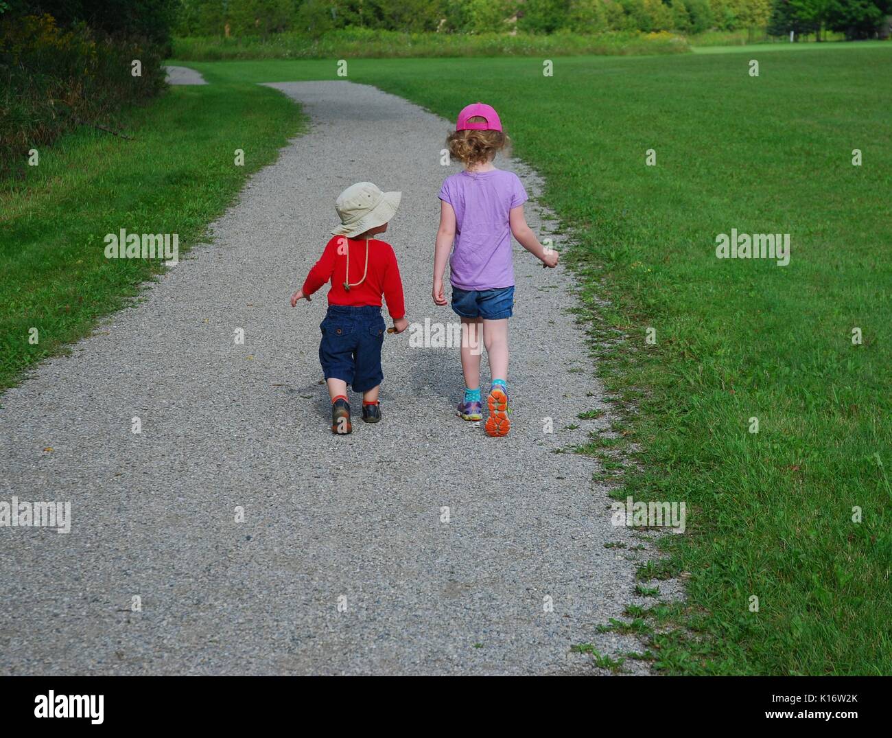 Little brother looking up at big sister on a walk Stock Photo - Alamy