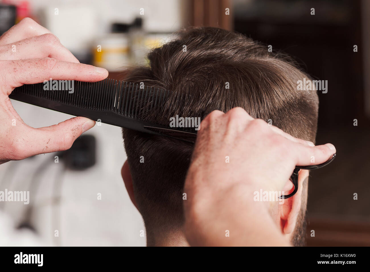 The hands of barber making haircut to young man in barbershop Stock ...