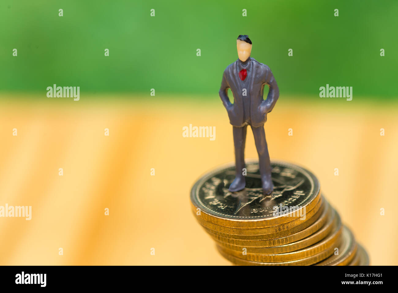 Miniature people, small figures businessmen stand on top of coins ...