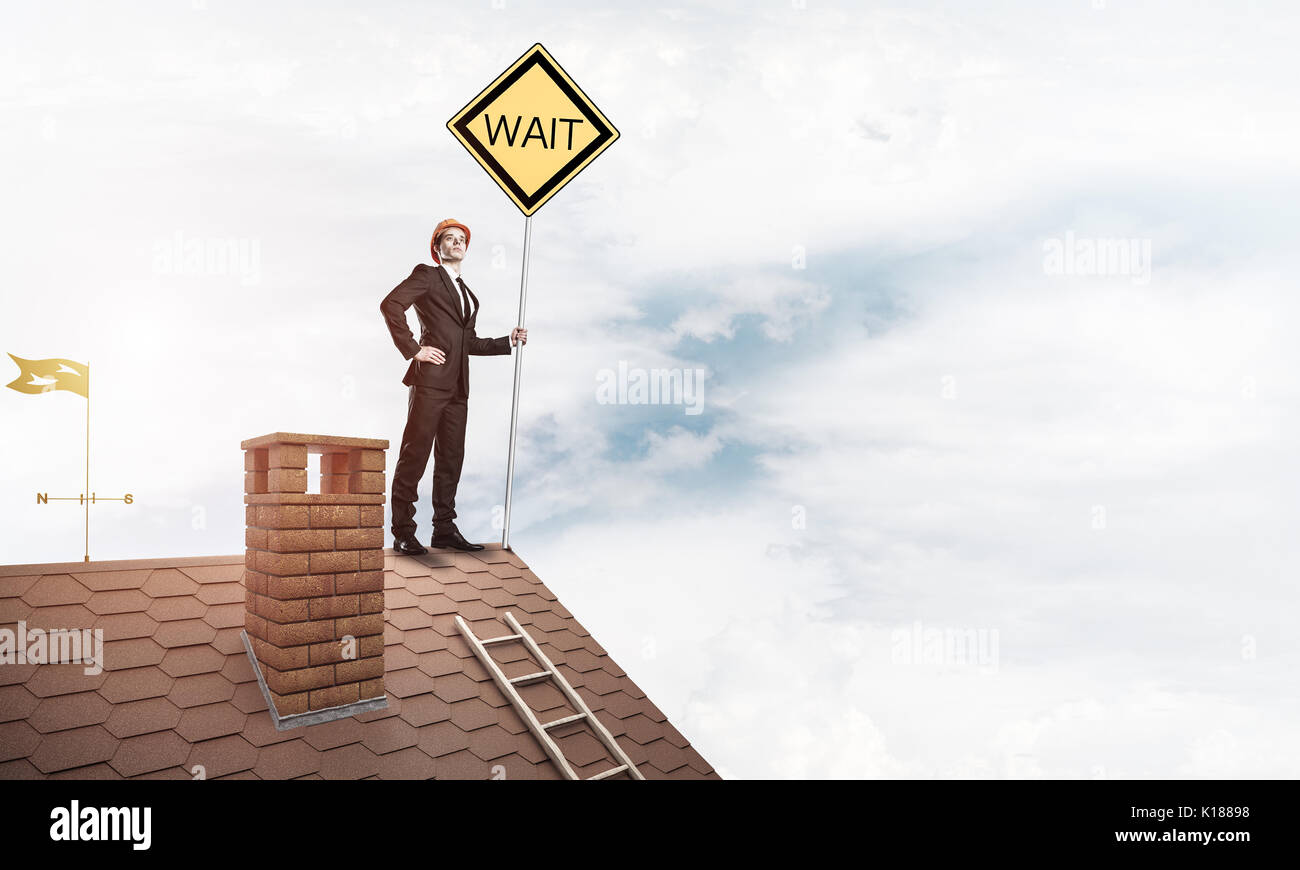 Young businessman on house brick roof holding yellow signboard Stock ...