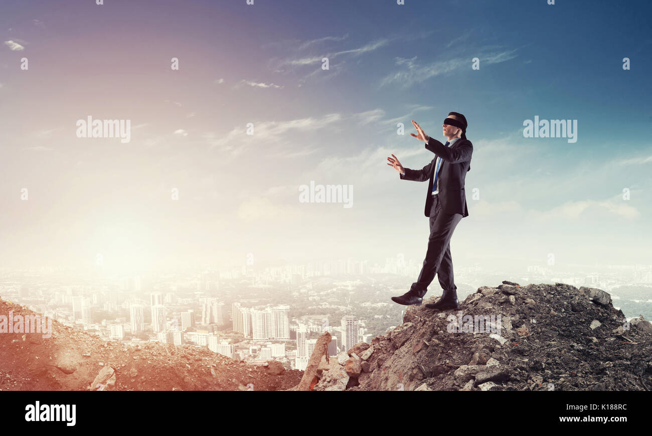 Young businessman in blindfold walking carefully and cityscape at background Stock Photo - Alamy