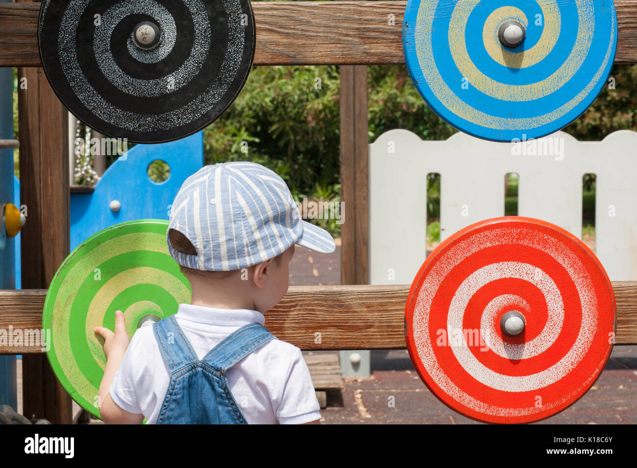 2 year-old boy playing with wooden colored disc with spiral draw in ...