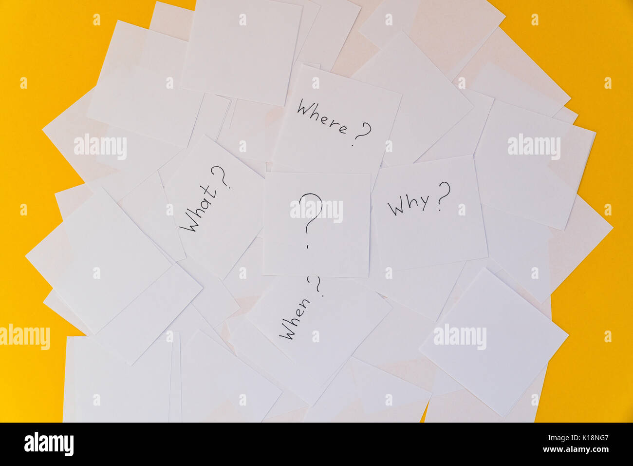 White square sheets of paper with questions spread out in chaotic order ...