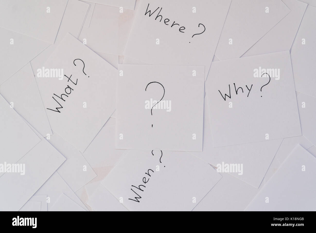 White square sheets of paper with questions spread out in chaotic order ...