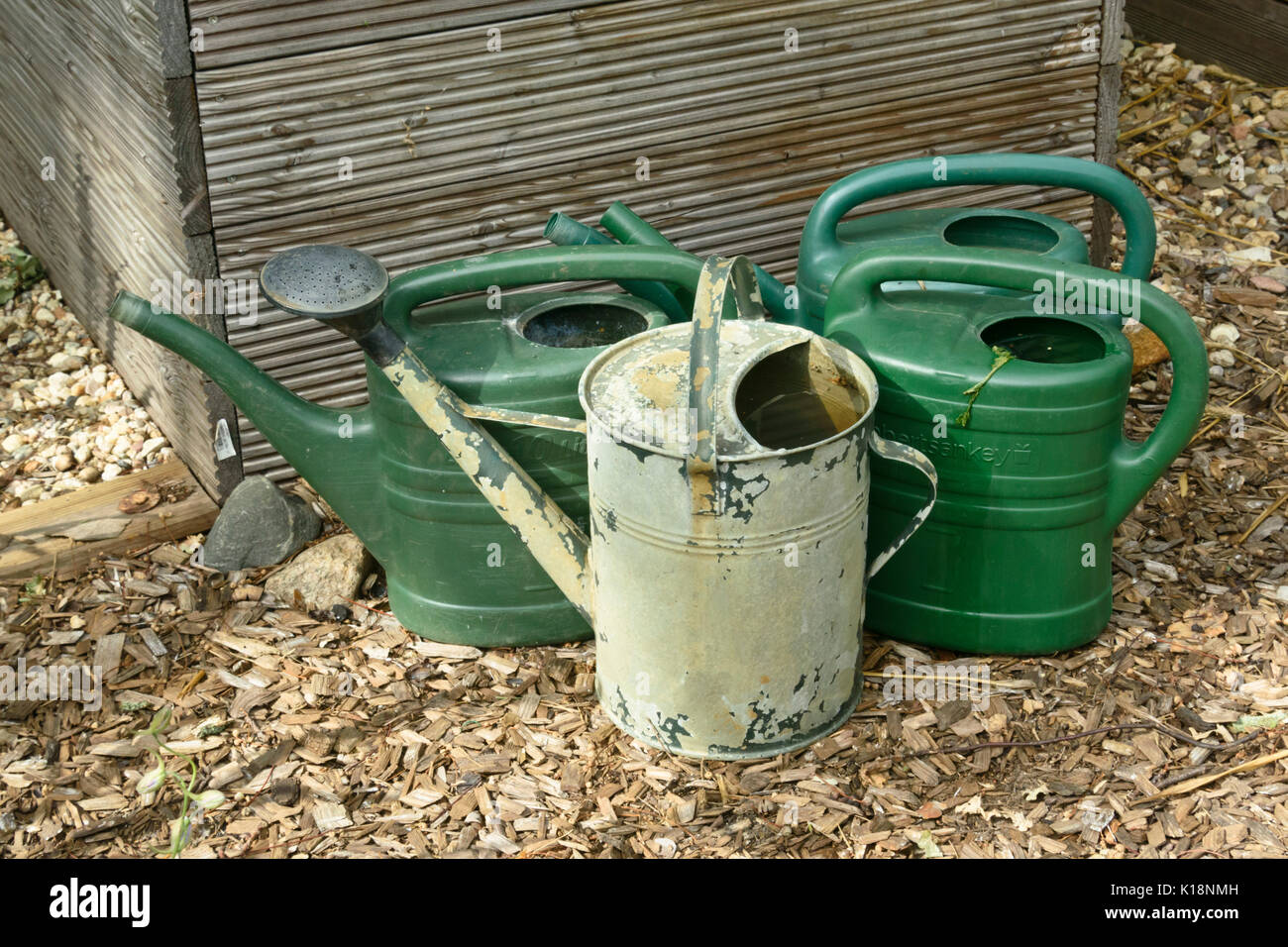 Watering cans in front of a raised bed Stock Photo - Alamy