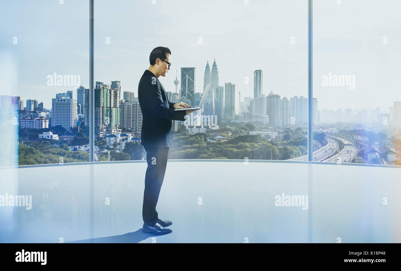 Businessman using laptop with generic office background , night scene ...