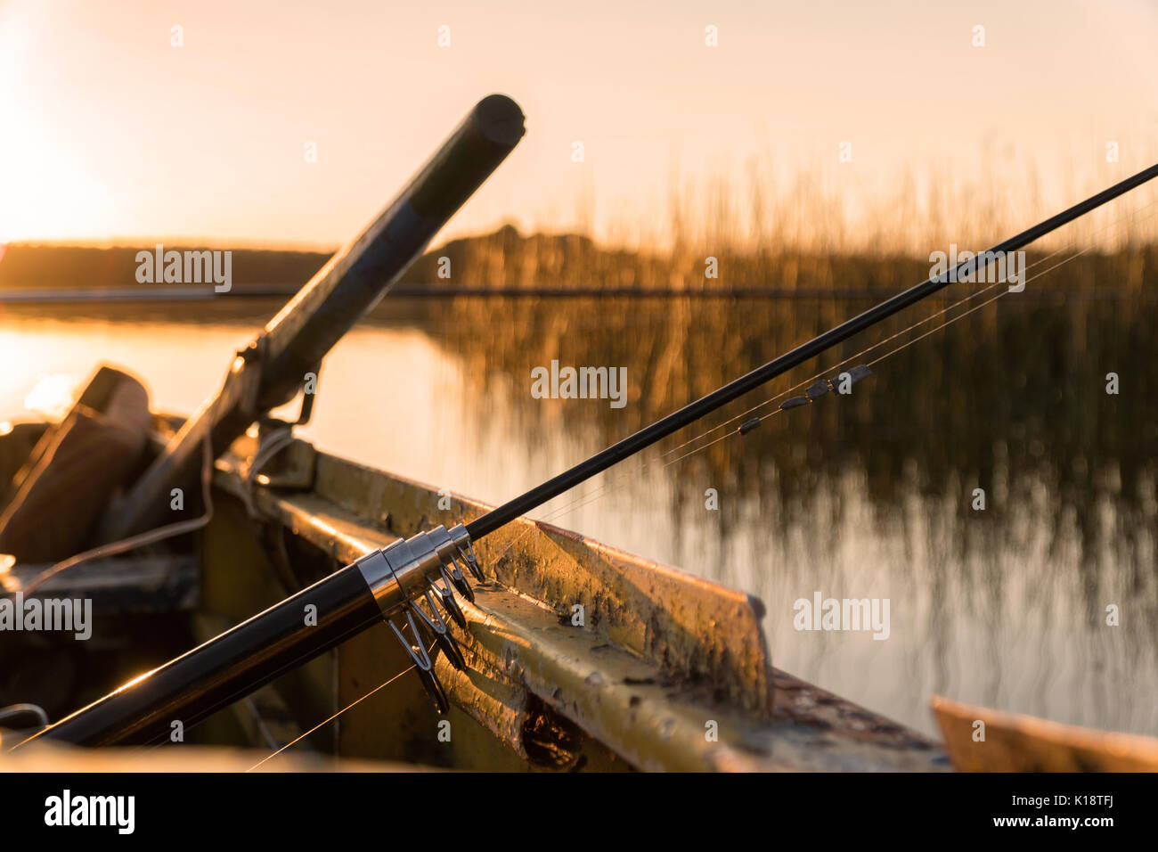 A broken fishing rod lies at the side of the boat at sunset Stock Photo ...