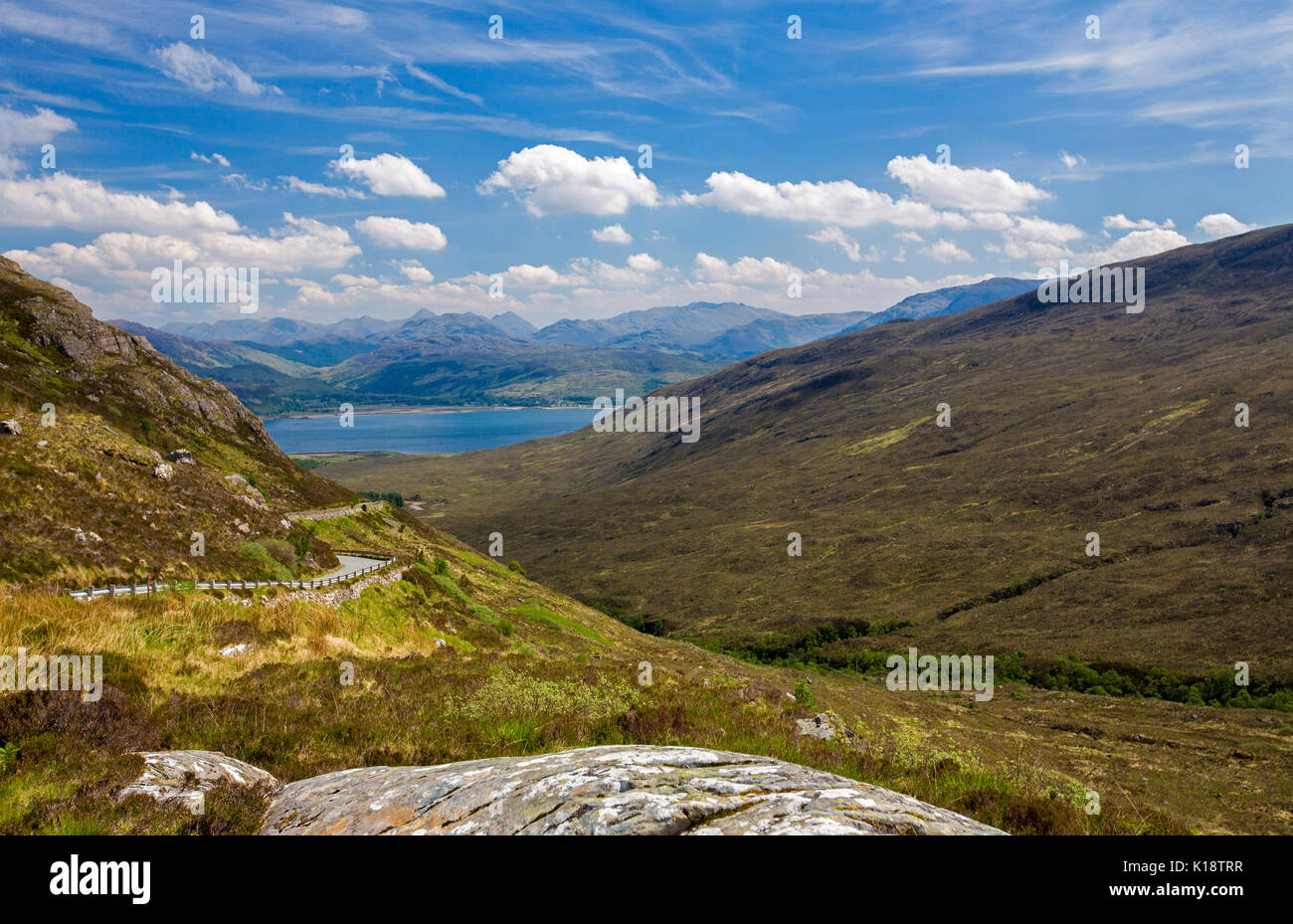 Winding road leading through treeless hills to ocean strait at Kylereah ...