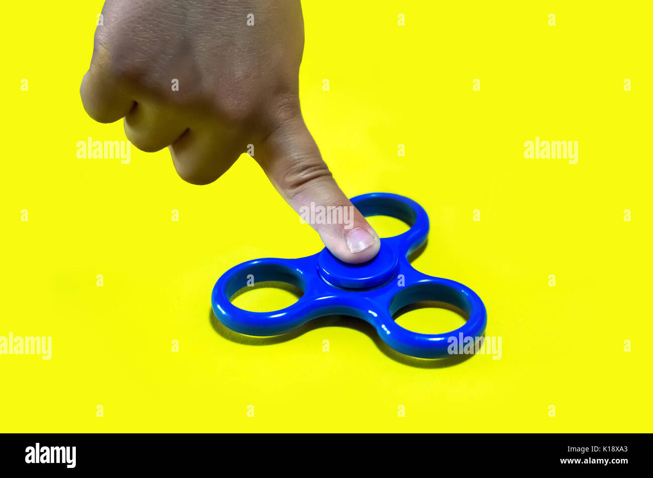 Anonymous man holding a fidget spinner isolated against yellow ...