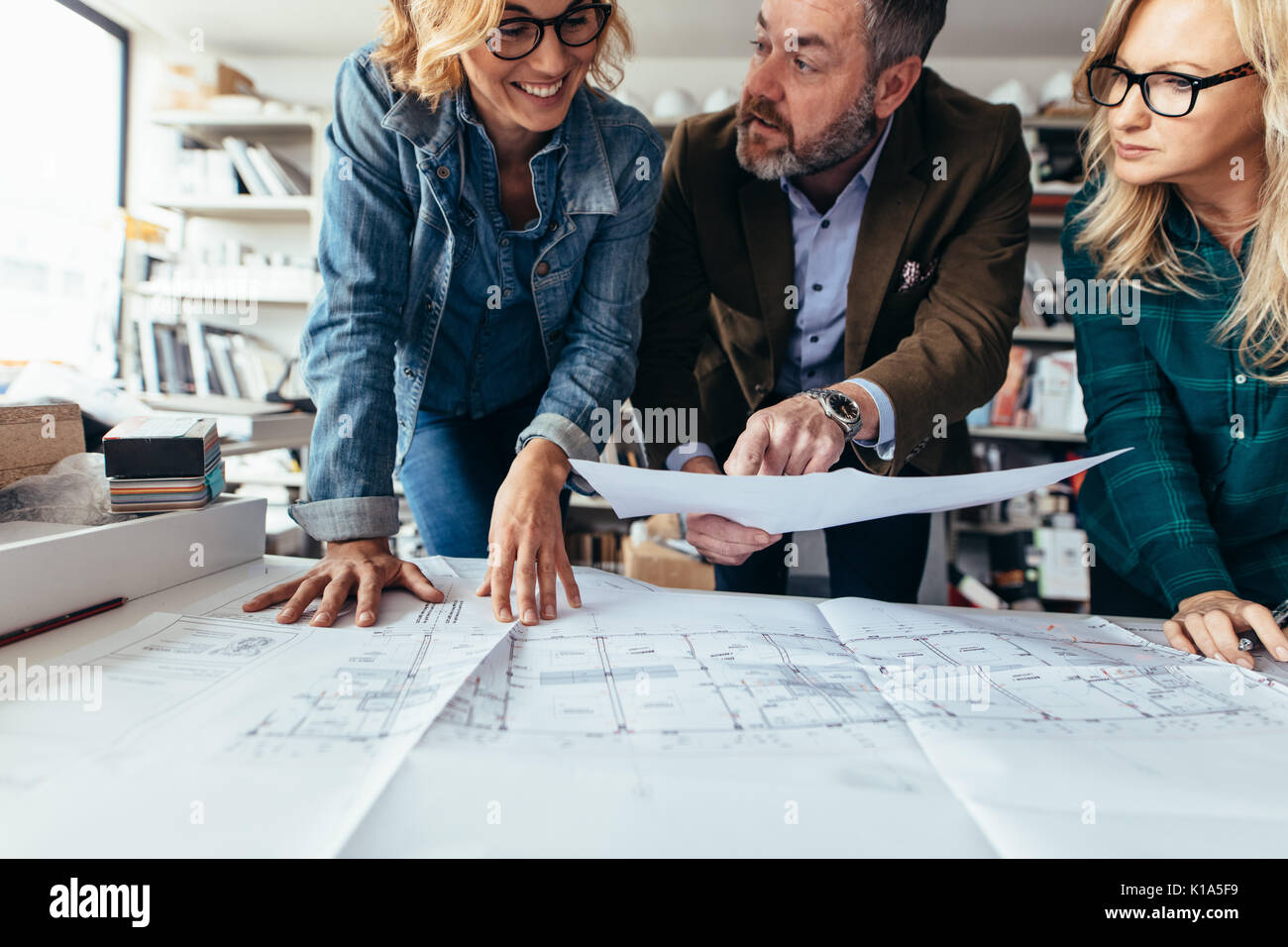 Group of business people with blueprints indoors. Three business people ...