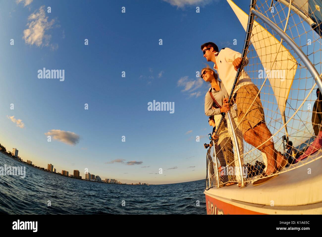 Attractive young couple on catamaran sailboat during sunset cruise on ...