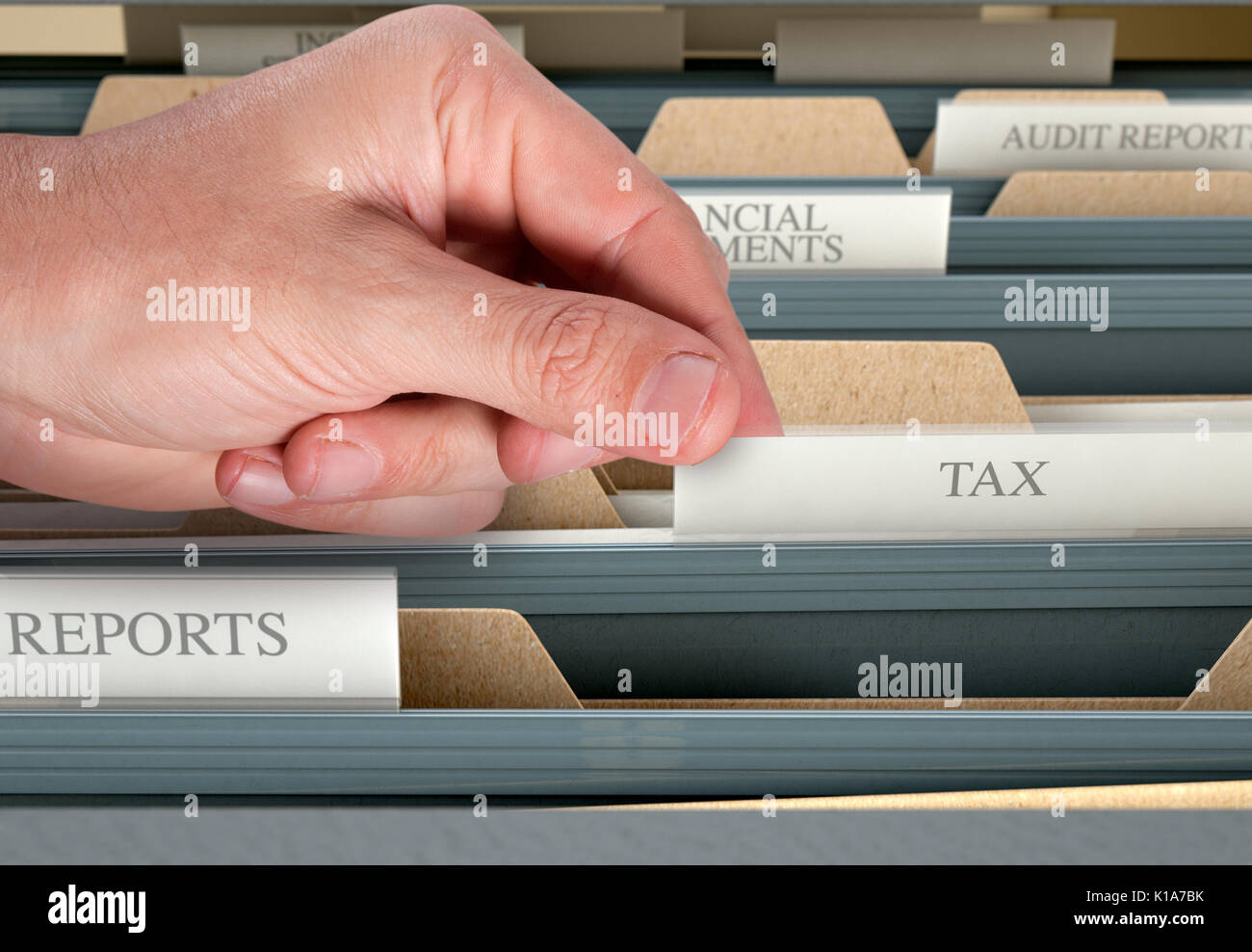 A male hand searching through documents in a filing cabinet drawer ...