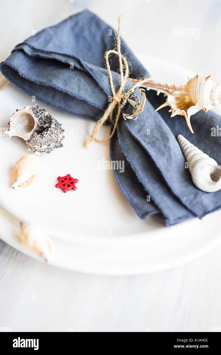 Summer vacation marine table setting with rustic plates and silverware ...