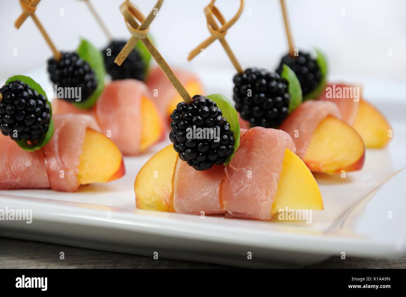 Canape from peach with dried ham and blackberries Stock Photo - Alamy