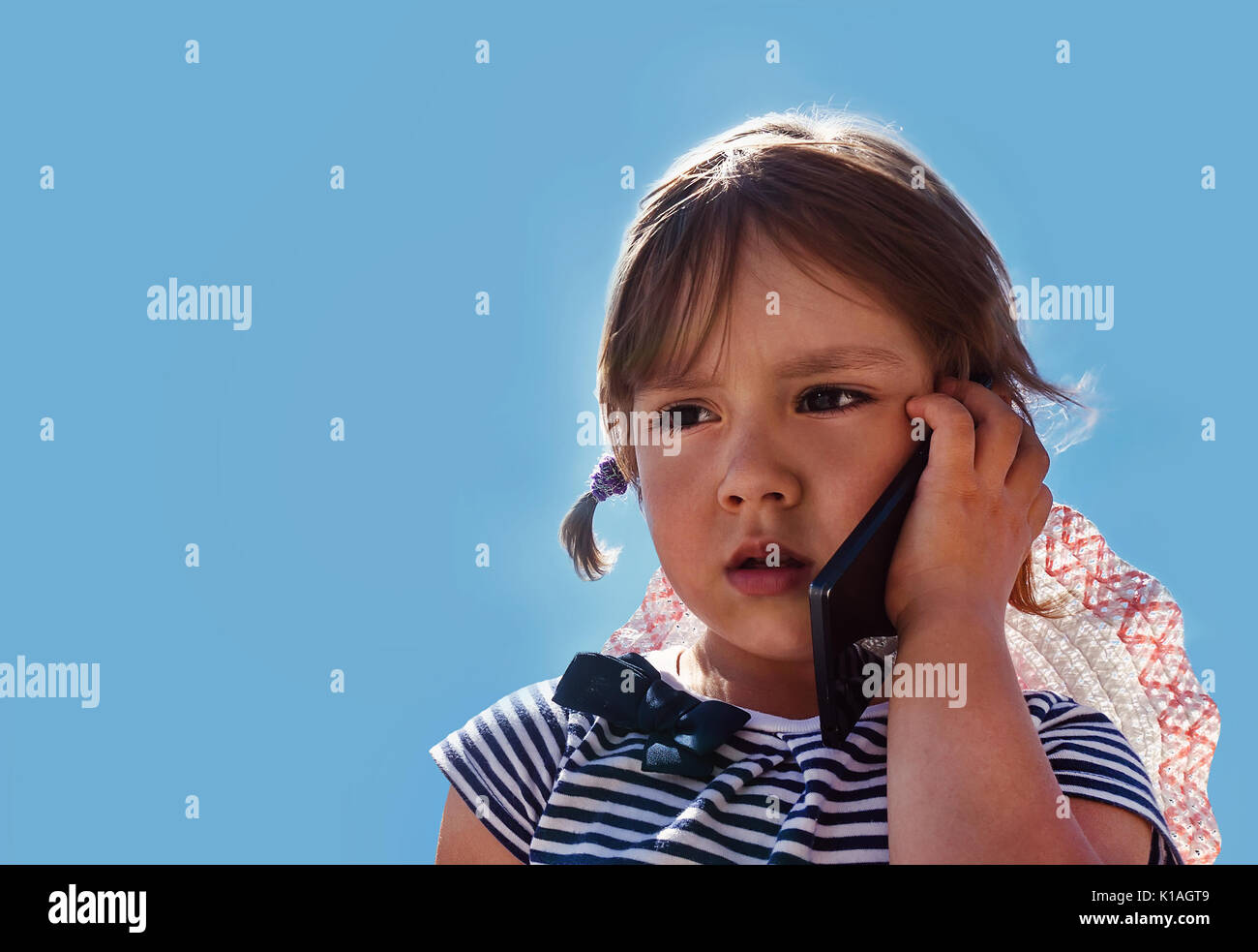 little girl with a unhappy look and sad eyes talking on the phone with ...