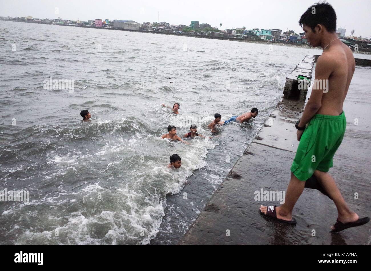Philippines. 25th Aug, 2017. A boy looks on as his friends swim among ...
