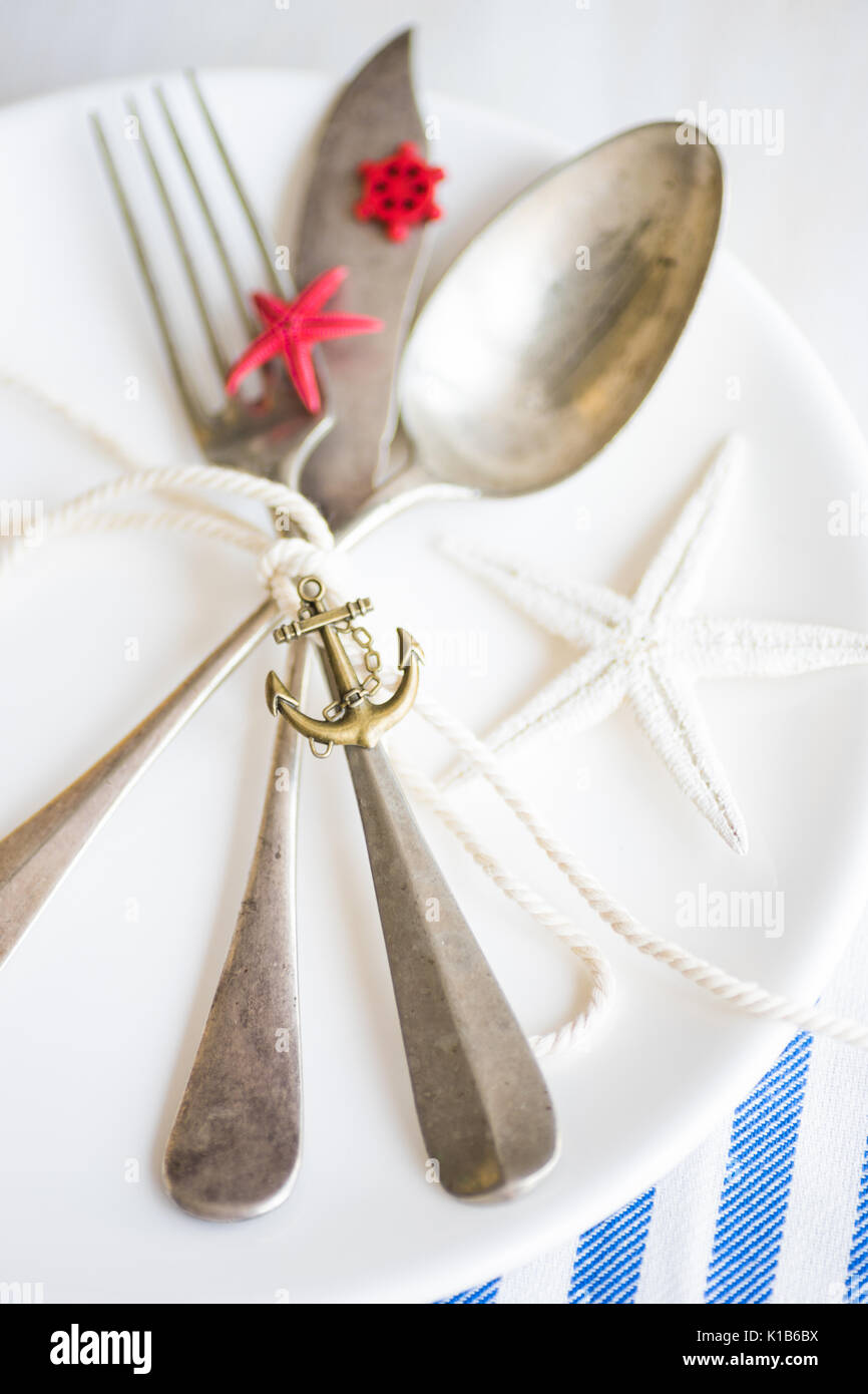 Summer vacation marine table setting with rustic plates and silverware ...