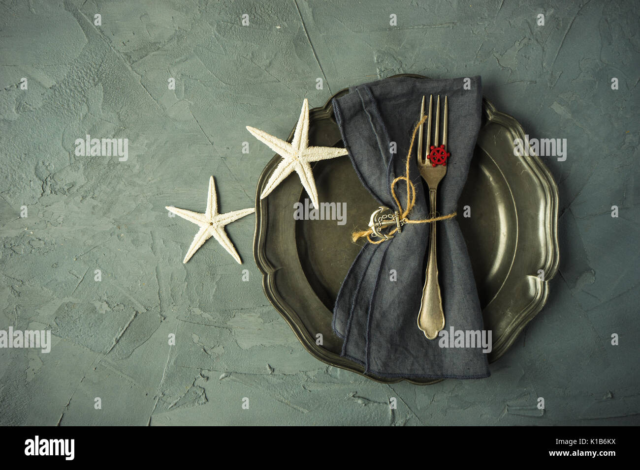 Summer vacation marine table setting with rustic plates and silverware ...