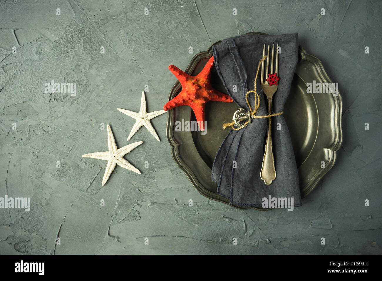 Summer vacation marine table setting with rustic plates and silverware ...