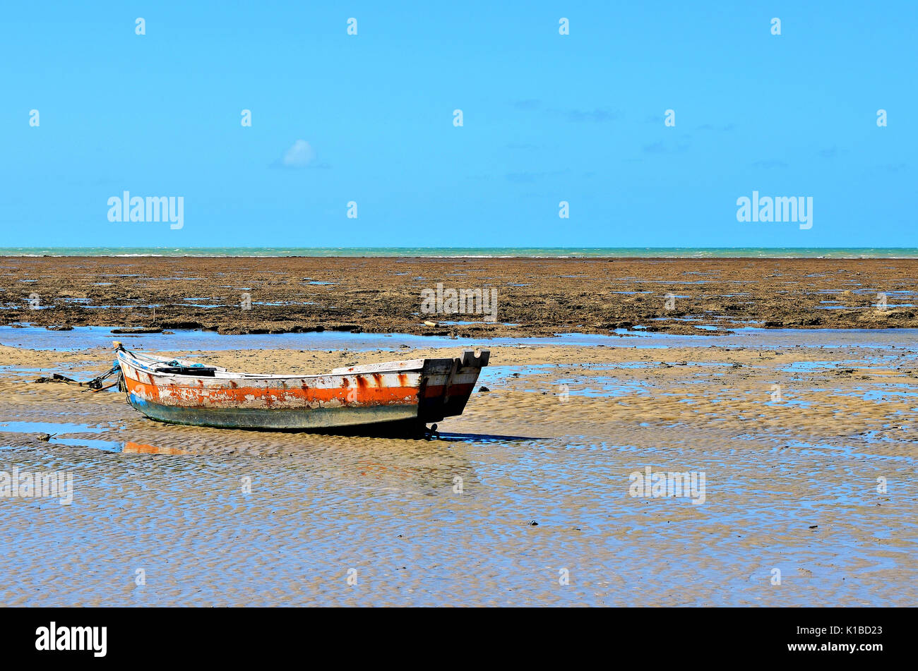 Small boat stranded during low tide with coral reef in the background ...