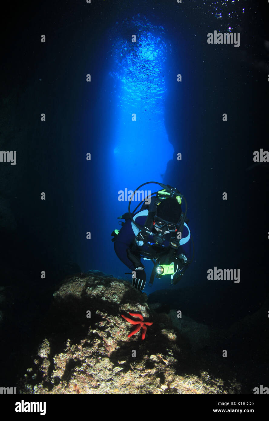 A scuba diver is exploring an underwater cave on Santa Maria island ...