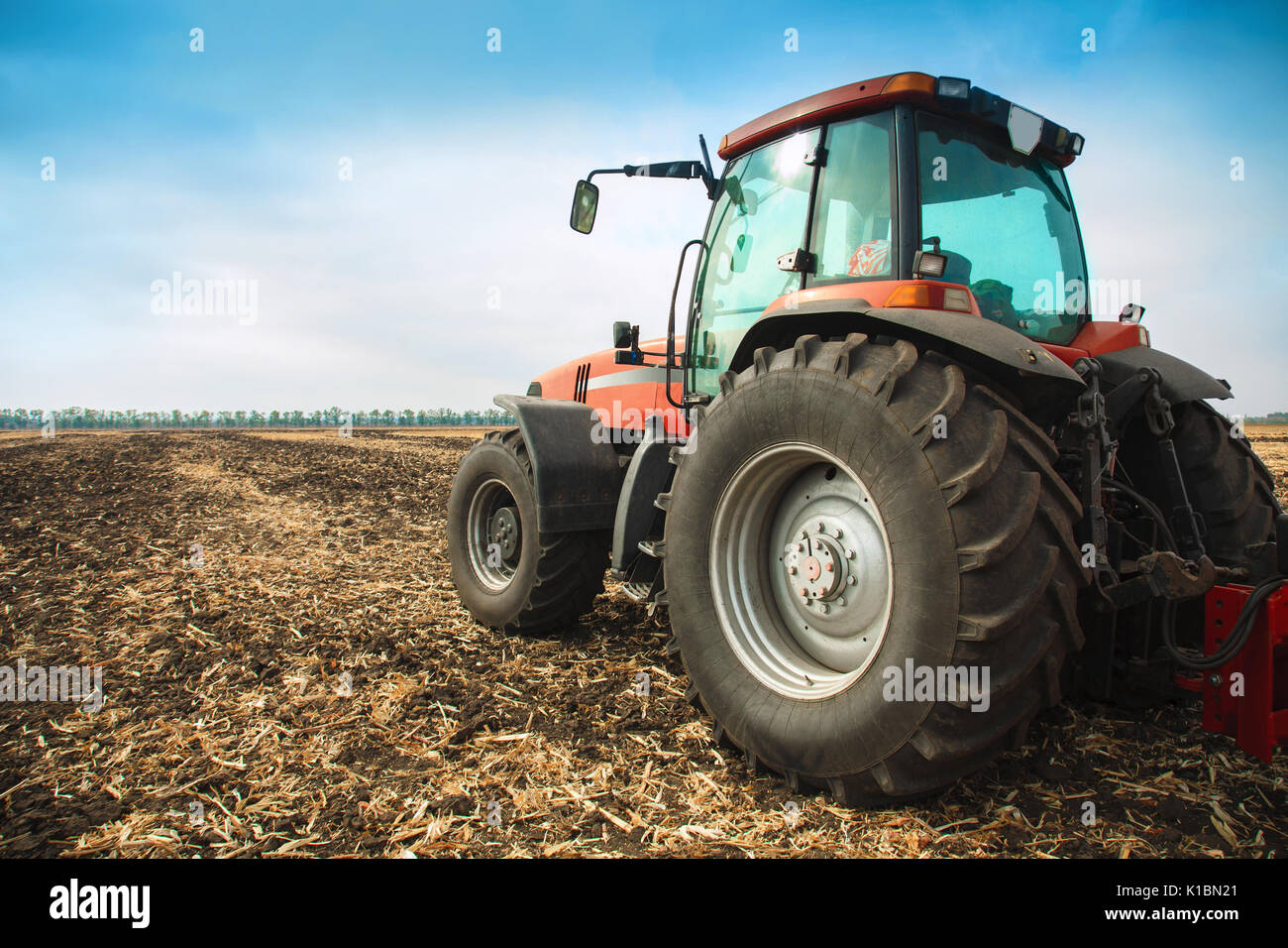 Modern red tractor in the field on a bright sunny day Stock Photo - Alamy