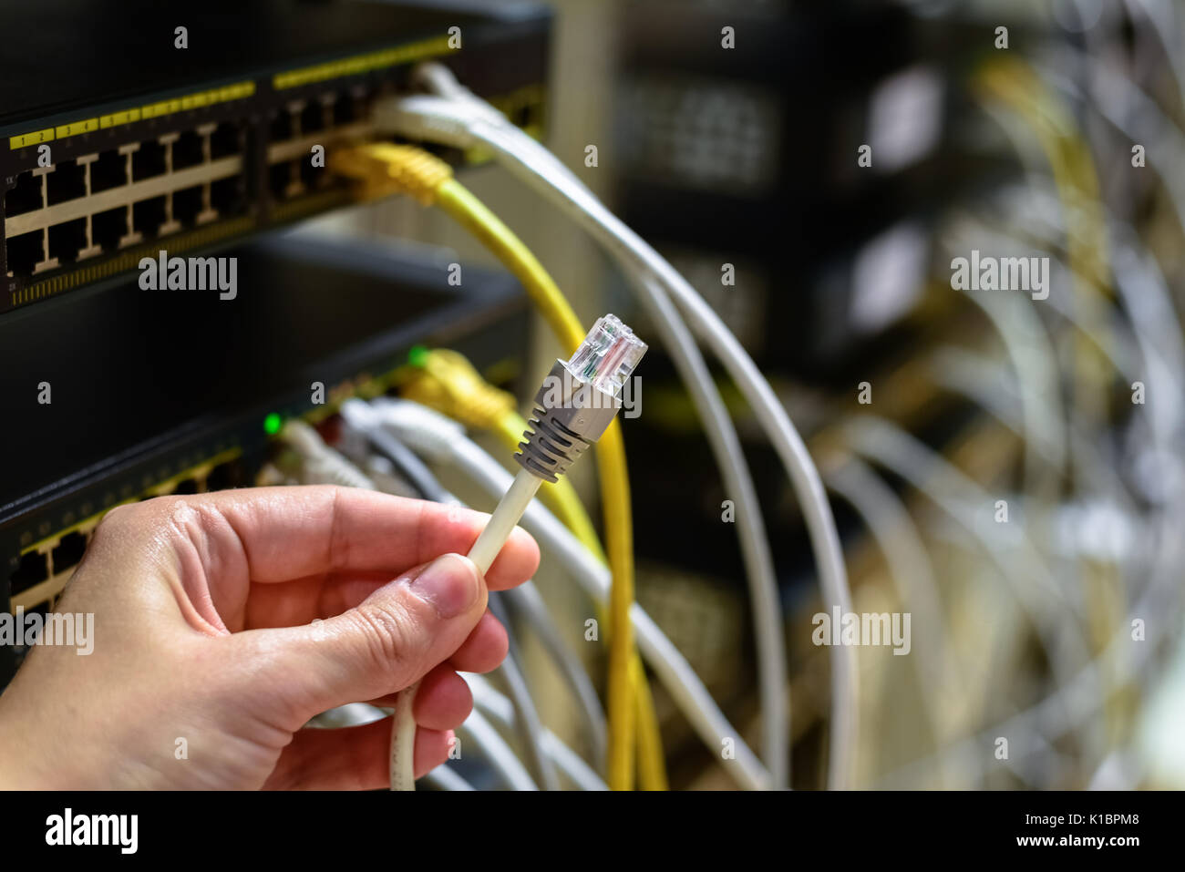Hand with rj45 cable and network equipment on background Stock Photo ...