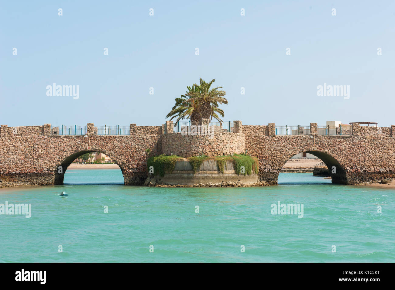 Large stone bridge over a tropical lagoon river with a pair of arches ...