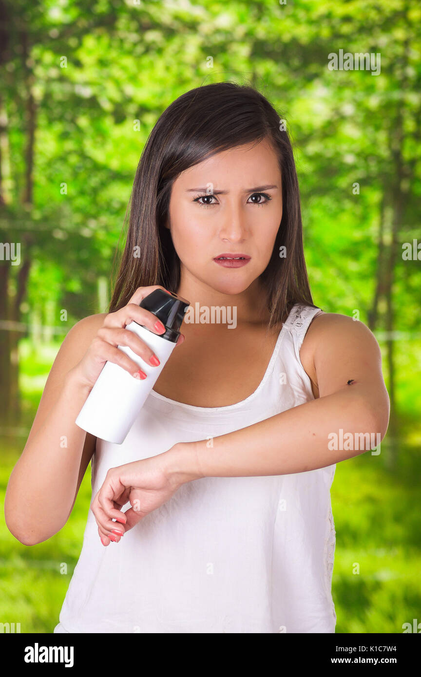 Beautiful young woman using a spay over the insect to kill it, in a ...