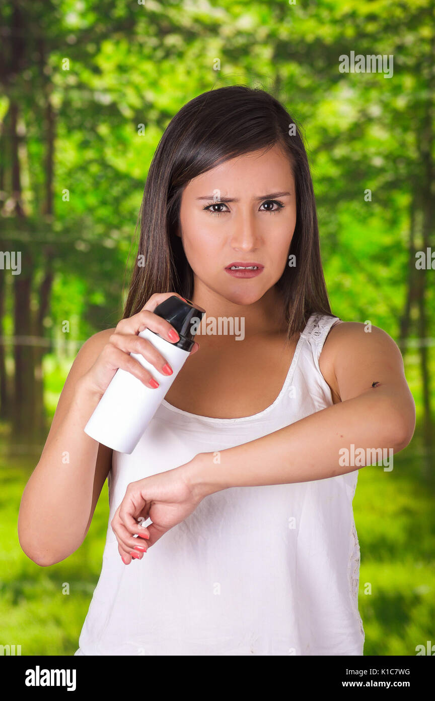 Beautiful young woman using a spay over the insect to kill it, in a ...