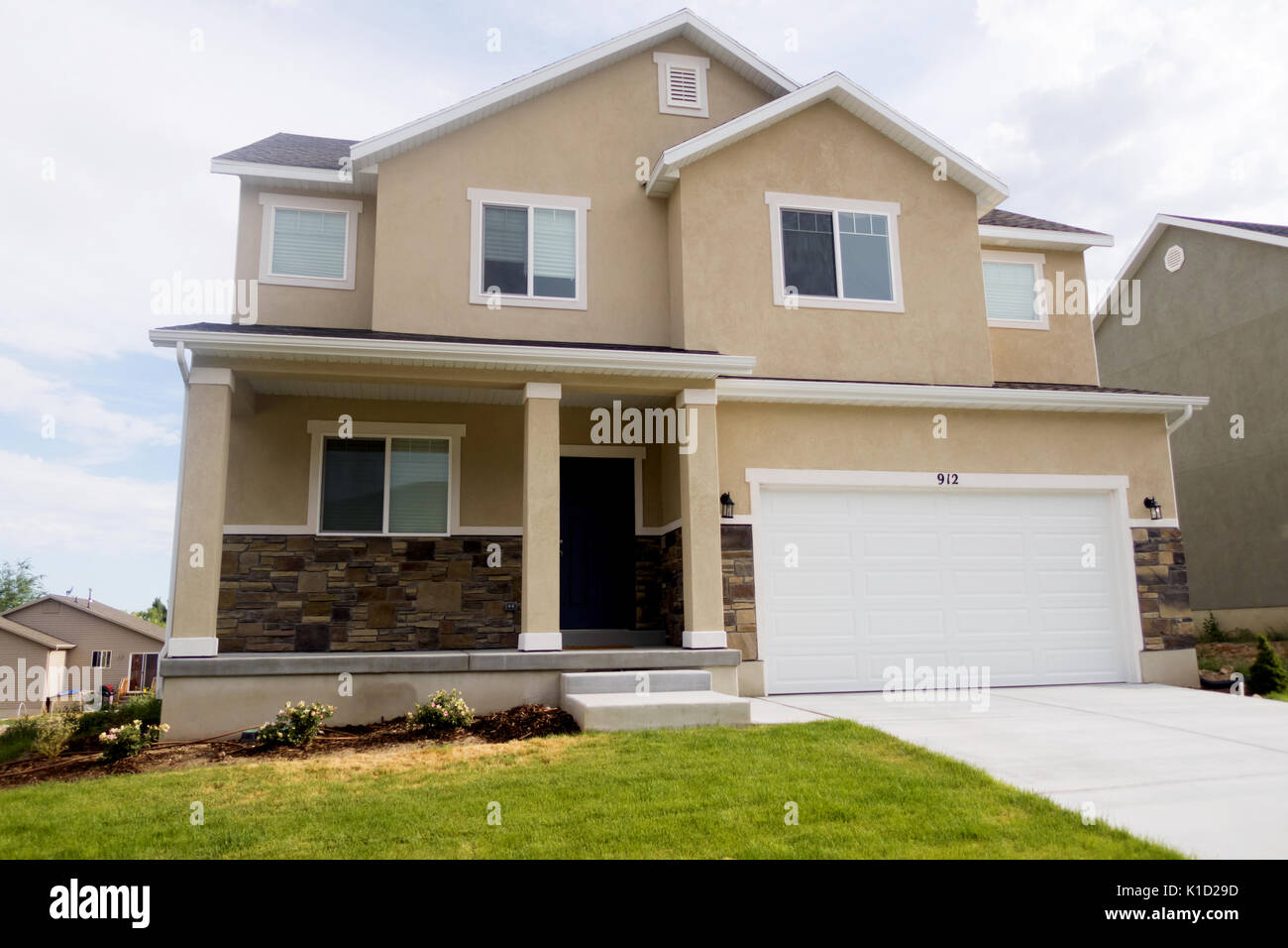 A new beautiful tan stucco and stone house with grass out front Stock ...