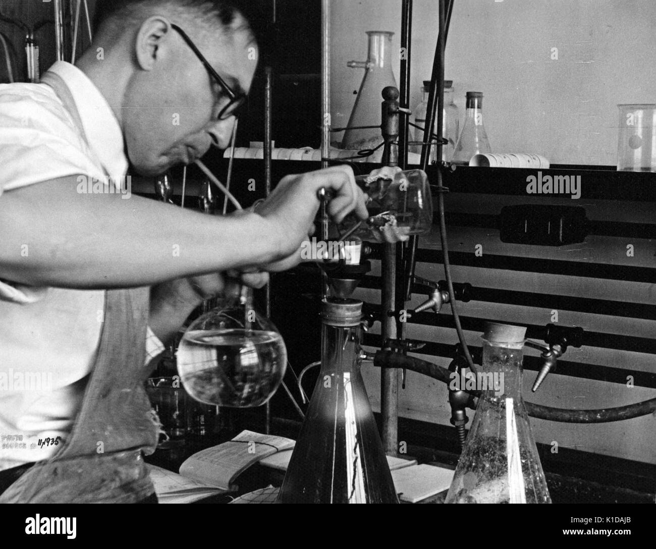 Scientist working with beakers in a laboratory while blowing into a ...