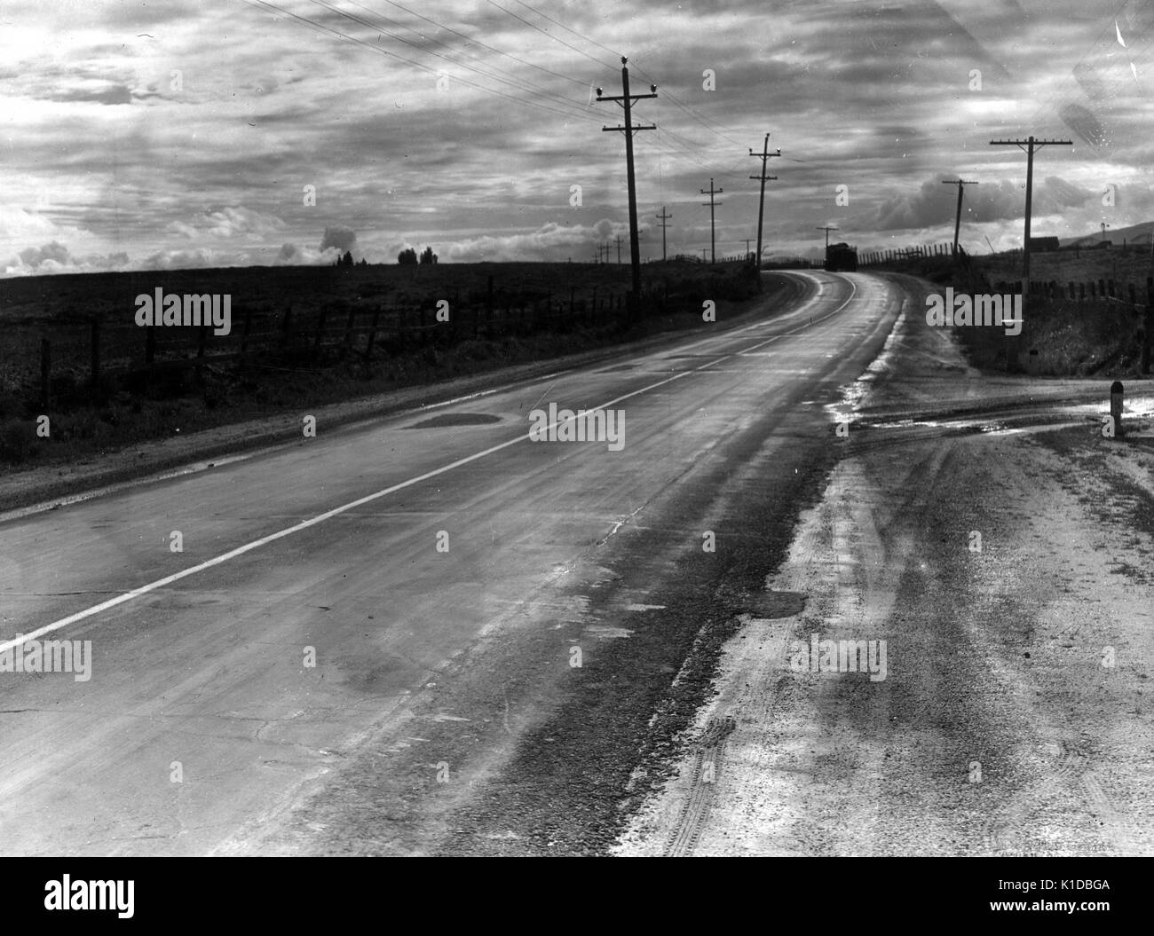 Starkly lit asphalt road receding into the distance, with telephone ...