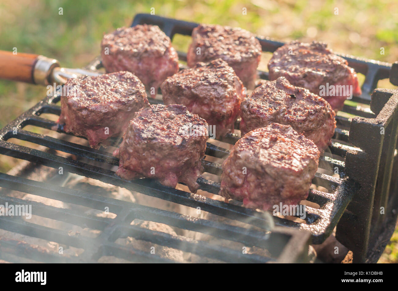 Mini beef sliders and fresh sea scallops being cooked on a charcoal ...