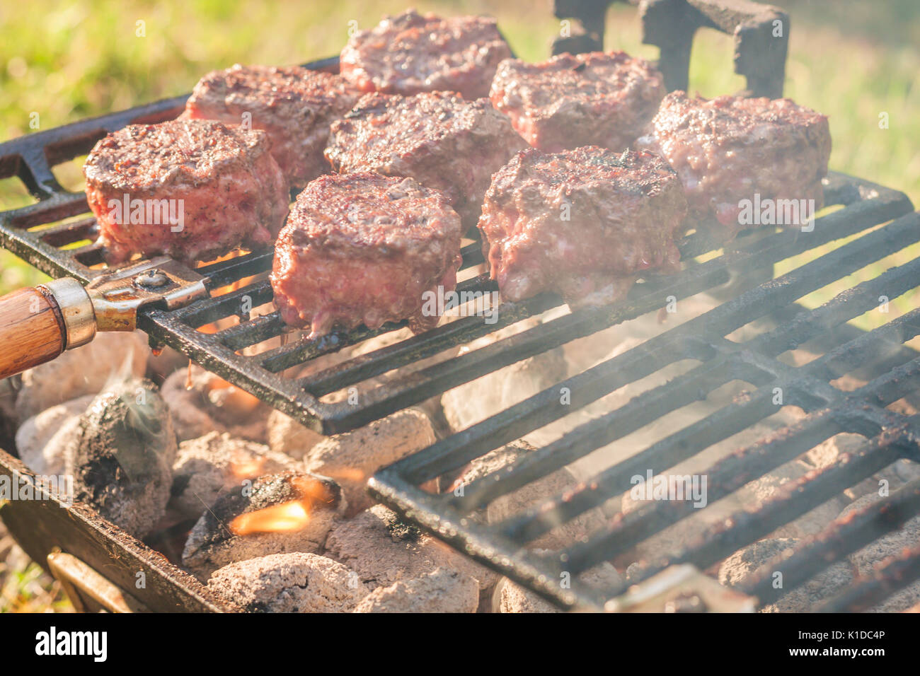 Mini beef sliders and fresh sea scallops being cooked on a charcoal ...