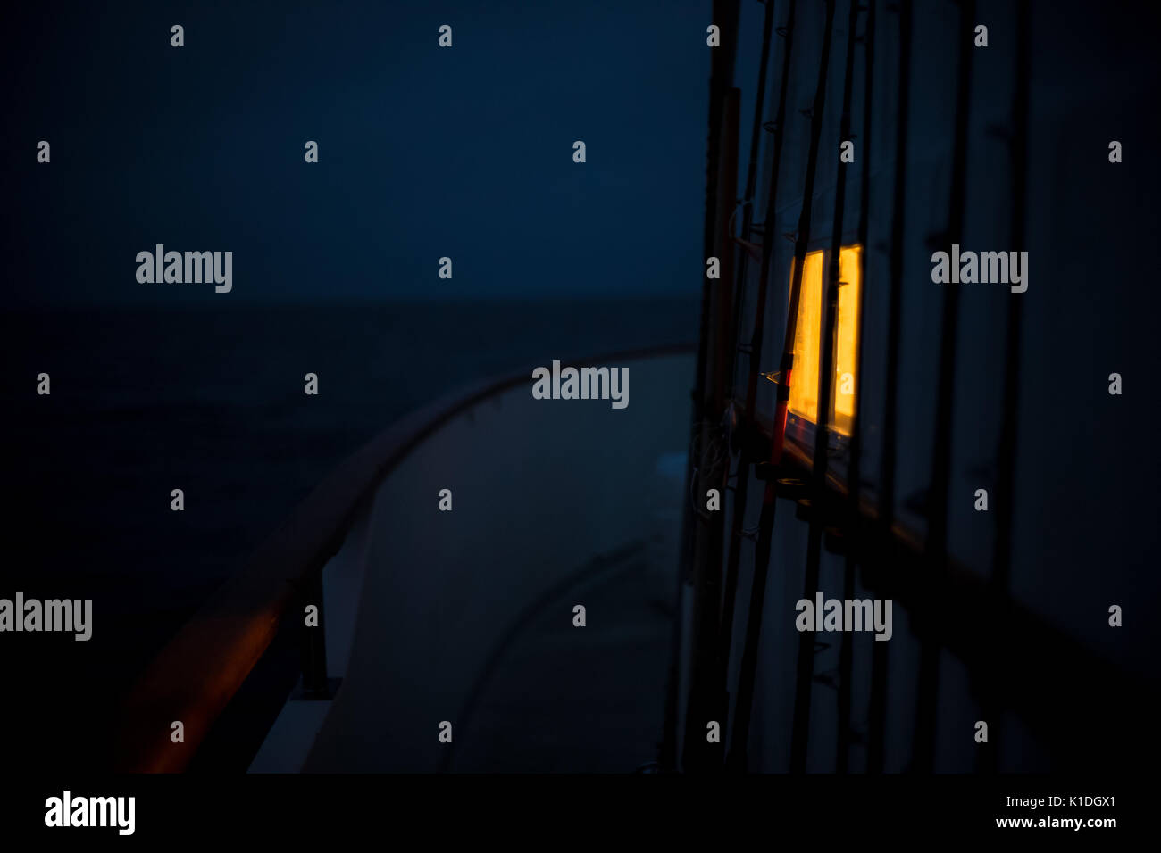 Warm light glows through a window on a fishing boat out at sea Stock ...