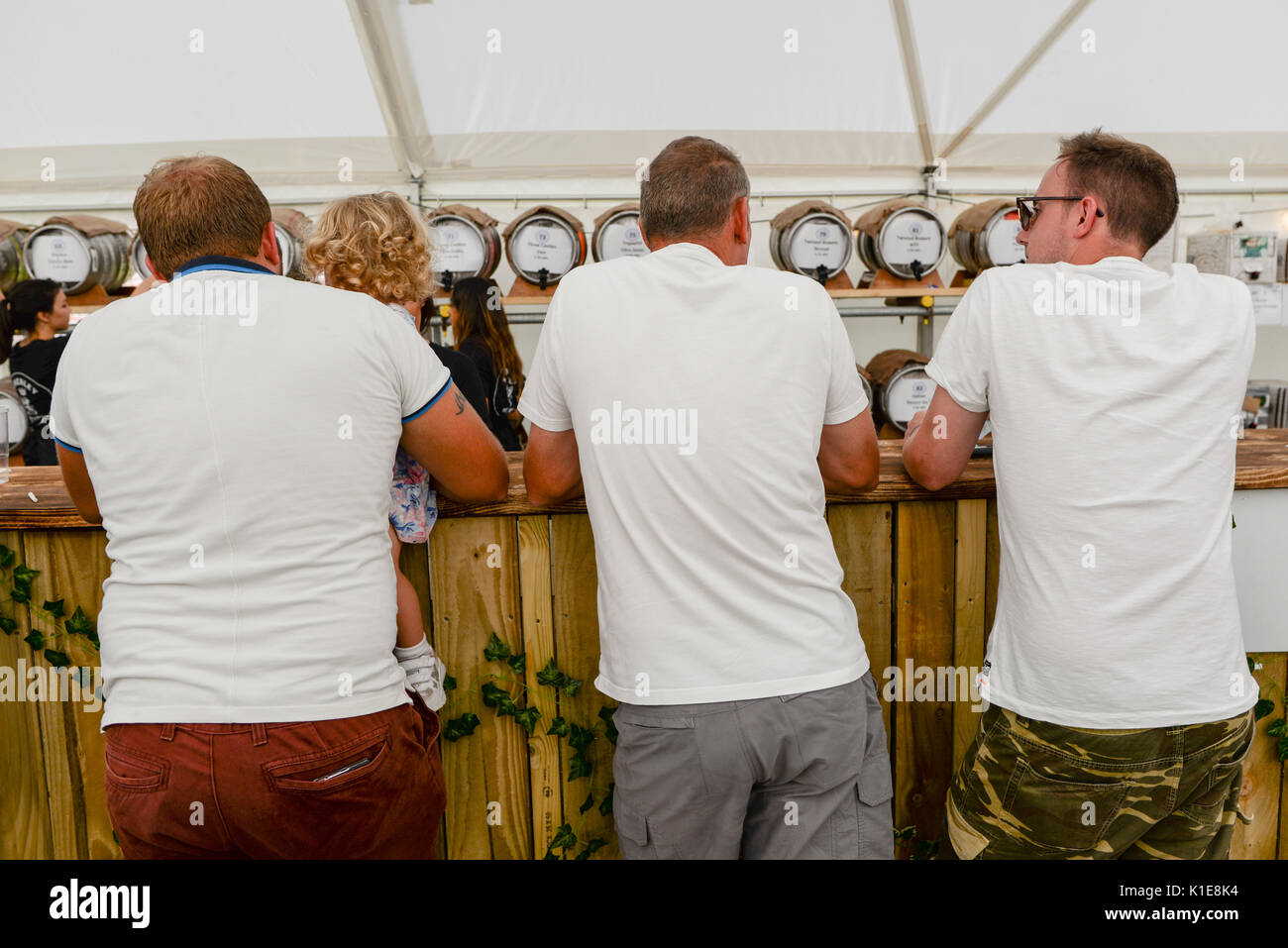 Three men at a bar and ordering drinks at a beer festival Stock Photo ...