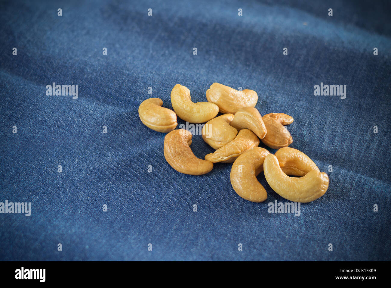 Roasted cashew nuts on blue canvas background (soft focus Stock Photo ...