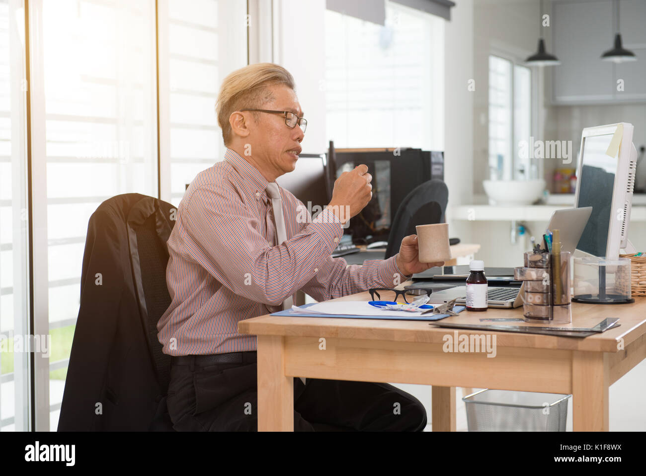 asian senior business man taking medicine at work Stock Photo - Alamy