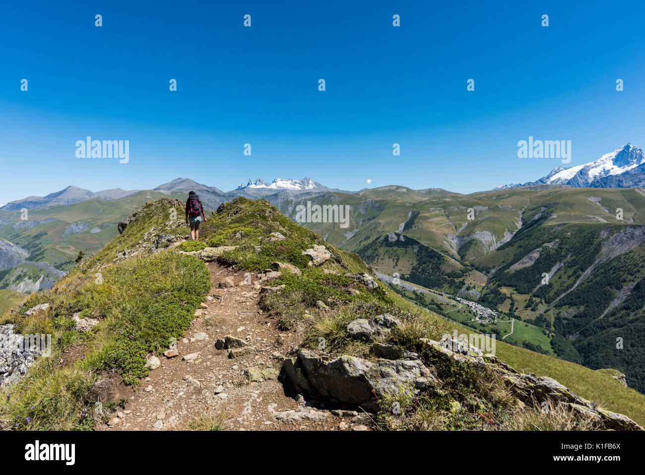 Hiker woman walking on a trail in the French Alps landscape with snowy ...