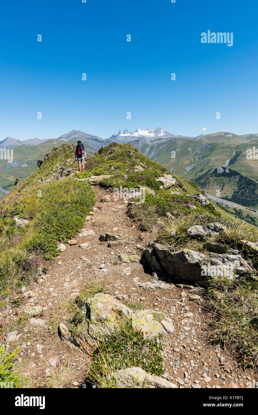 Hiker woman walking on a trail in the French Alps landscape with snowy ...