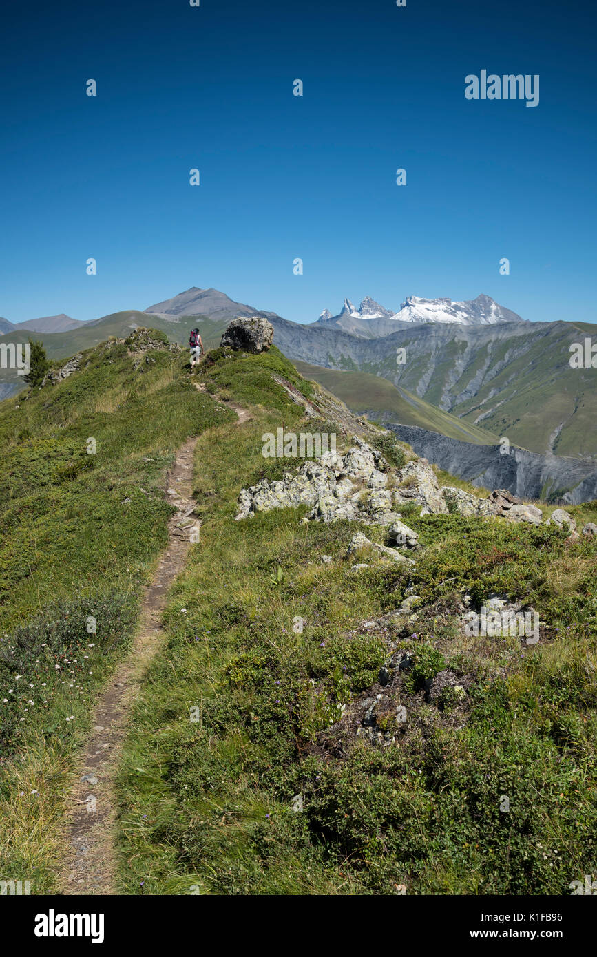 Hiker woman walking on a trail in the French Alps landscape with snowy ...
