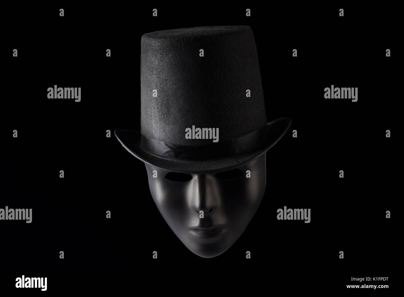 Black mask face wearing black top hat isolated on black background with ...