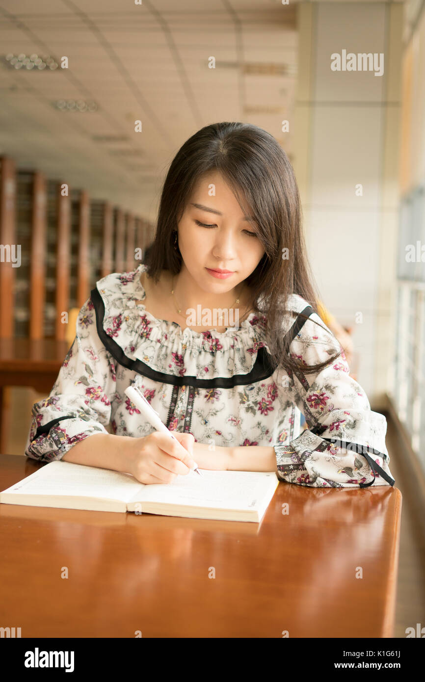 asian girl in library reading book Stock Photo - Alamy