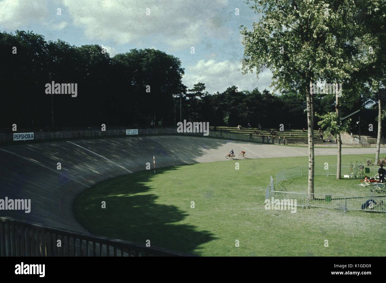 Two bikers racing on a concrete race track with green grass area in the ...