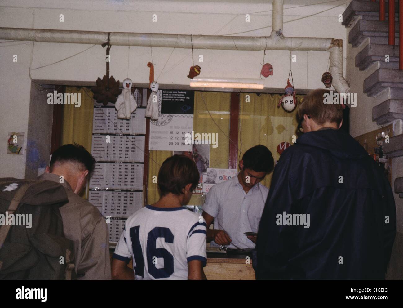 Three young men checking into a youth hostel, the proprietor of the ...