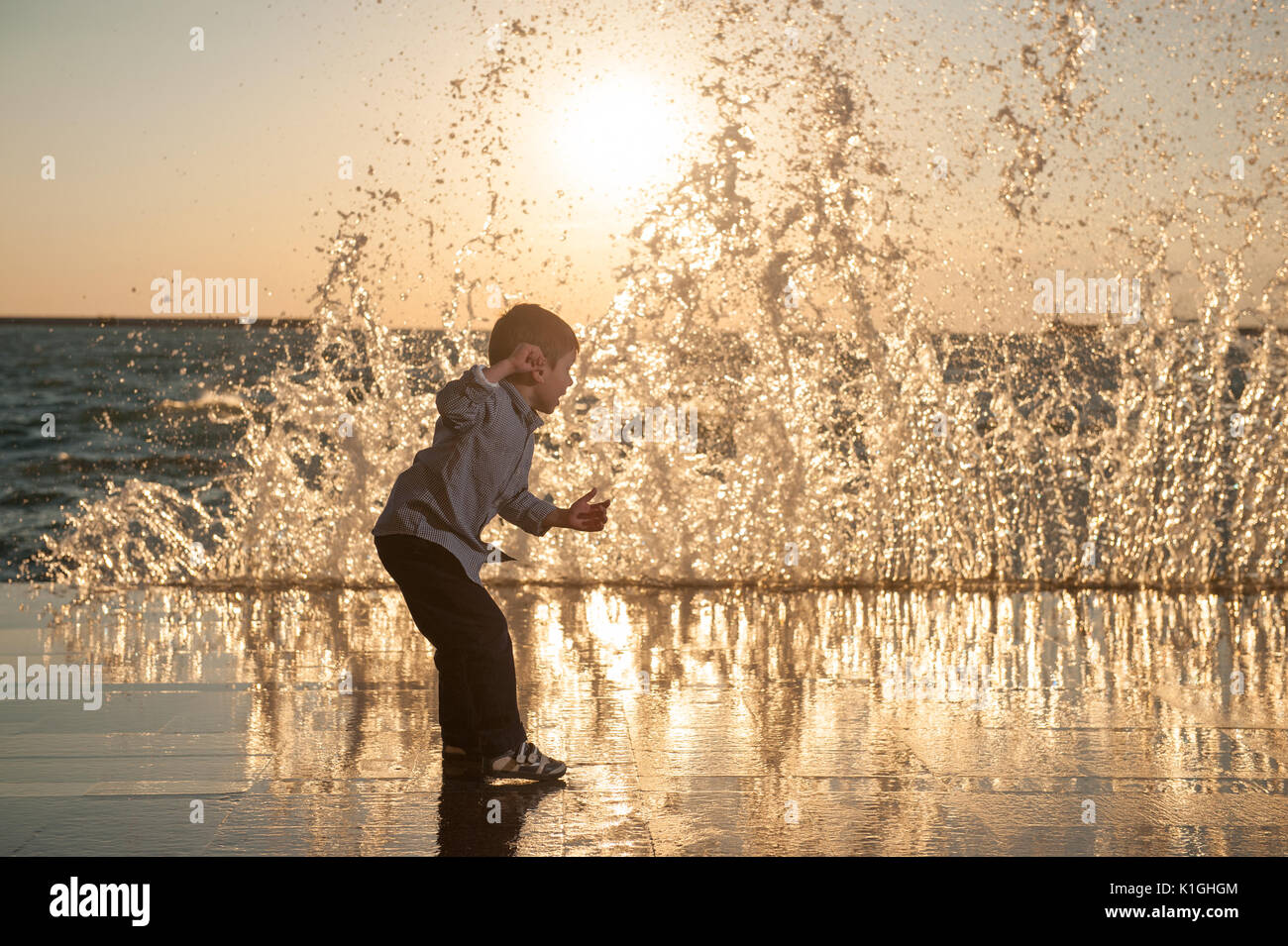 amazed little boy trying to escape from huge waves on ocean sunset ...